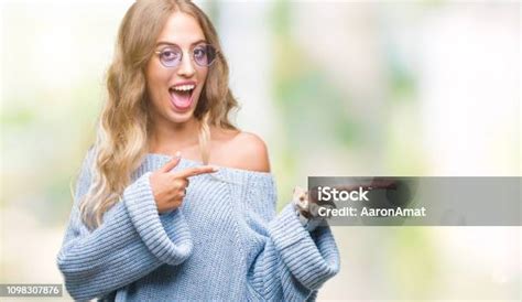 아름 다운 젊은 금발 여자 놀라게 했 고 손으로 제시 하 고 손가락으로 가리키는 동안 카메라에 웃 고 고립 된 배경 위에 선글라스를 착용 가리키기에 대한 스톡 사진 및 기타