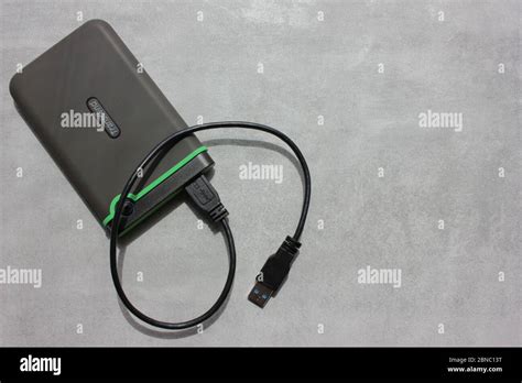 Gray And Green External Hard Drive For Backup With Usb Cable On Gray Concrete Background With