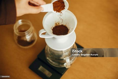 필터에 접지 커피를 붓는 손은 규모의 유리 주전자에 부어 대체 커피 양조 V60준비 갈색 배경에 갈기 커피와 숟가락을 들고 있는
