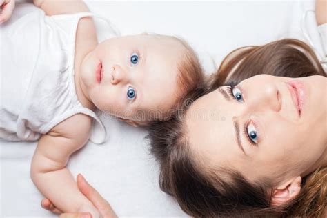 Счастливая мать при младенец лежа на белой кровати Стоковое Фото изображение насчитывающей
