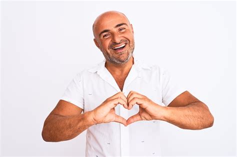 고립 된 흰색 배경 위에 서있는 우아한 셔츠를 입은 중년 잘생긴 남자는 손으로 심장 기호와 모양을 보여주는 사랑에 미소 로맨틱 한 개념 개념에 대한 스톡 사진 및 기타