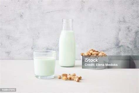 식물성 견과류 우유 한 잔이 피스타치오 우유와 피스타치오 한 병 옆 테이블에 있습니다 채식주의자를 위한 완벽한 음료 0명에 대한 스톡 사진 및 기타 이미지 Istock