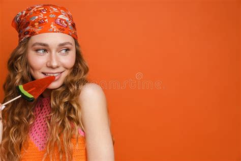 Young Ginger Woman Wearing Bandana Smiling While Licking Lollipop Stock