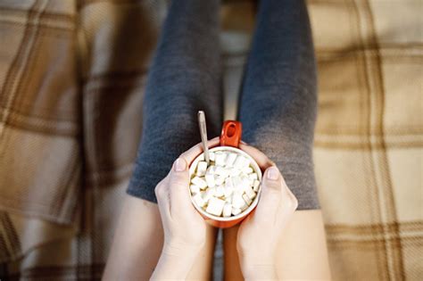 위에서 붉은 격자 무늬의 배경에 마쉬 멜 로우 코코아 컵을 들고 그의 손에 따뜻한 스웨터에 여자로 서 보기 경관에 대한 스톡 사진 및 기타 이미지 Istock