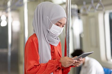 Asian Muslim Woman Wear Hijab Head Scarf And Using Mobile Phone In The