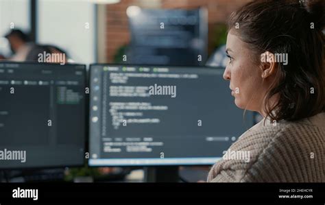 Over Shoulder View Of Focused Database Designer Writing Code Looking At Multiple Computer