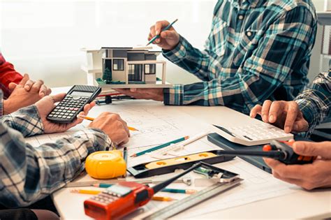 건축가가 디지털 태블릿을 들고 새로운 부동산 프로젝트를 진행하면서 책상에 앉아 엔지니어링 도구와 건축 모형 집 건물 및 시공을 클로즈업하는 장면 개인 장식품에 대한 스톡