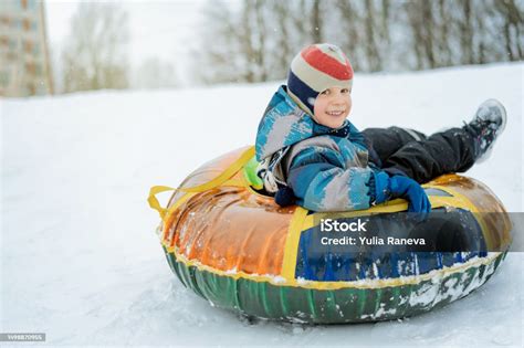 귀여운 백인 초등학생 소년이 공원에서 슬로프를 미끄러지듯 내려오고 있다 겨울 활동 개념입니다 행복한 어린 시절 선택적 초점이 있는 이미지 겨울에 대한 스톡 사진 및 기타