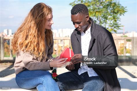 아프리카 흑인 남자와 빨간 머리 백인 여자 장미 와 과자 와 심장 모양 상자를 열고 발렌타인 데이를 축하하는 젊은 다인종 커플 2명에 대한 스톡 사진 및 기타 이미지