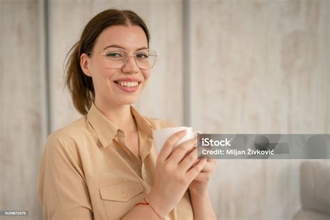 한 여성 젊은 성인 백인 여성이 직장 앞 모습 허리 위로 복사 공간 착용 셔츠에 사무실 책상에 서서 안경을 쓰고 행복한 미소를 짓고 있다 25 29세에 대한 스톡 사진 및