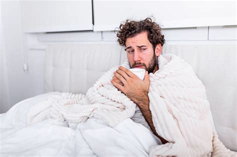 집에서 아픈 날 잘생긴 남자는 발열과 감기가 있습니다 기침 감기 또는 독감 병을 잡은 젊은 남자의 클로즈업 건강에 해로운 남자의 초상화 목구멍에 통증을 느끼고 뜨거운 음료를