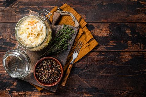 홈메이드 소금에 절인 양배추 후추 백리향이 있는 유리 항아리 나무 배경 맨 위 보기입니다 복사 공간 갈기갈기 찢어진에 대한 스톡