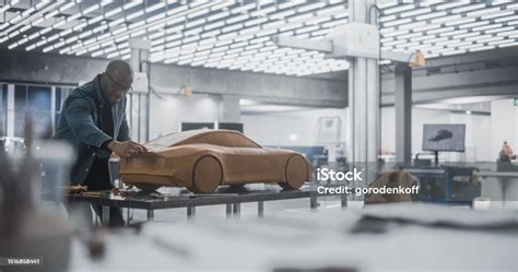 주걱을 사용하여 폴리머 모델링 점토로 프로토타입 자동차를 만드는 아프리카 자동차 디자이너 자동차 생산 공장의 연구 개발