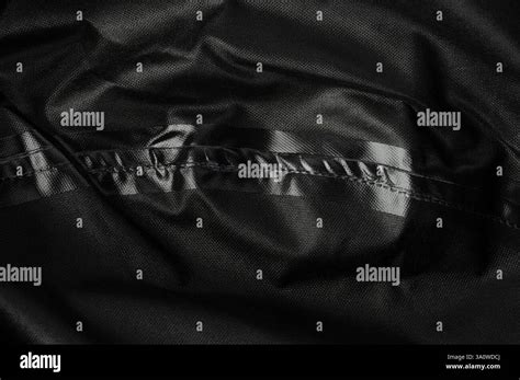 Close Up Of Black Fabric Displaying Shiny Stripe Pattern Under Dim Lighting Highlighting