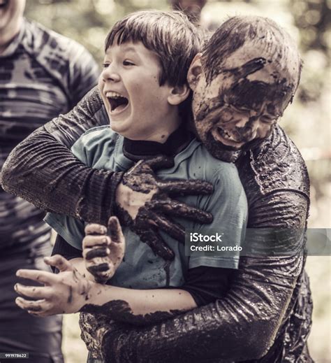Father And Son Having Sporty Fun At A Public Mud Run Obstacle Course