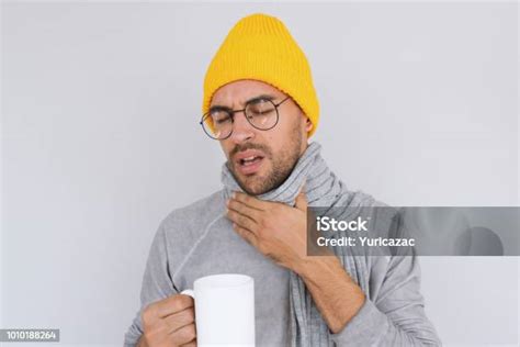 불행 한 잘생긴 수염된 남자 목이 인플루엔자 데입니다 아픈 사람 통증에서 고통 찡그린 그의 목 감동 입고 노란색 모자 회색 스웨터와 스카프의 초상화 사람 건강 의학 남자에