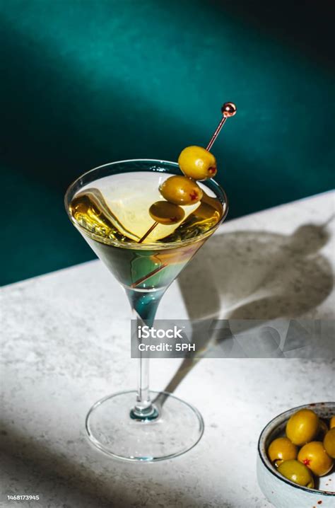 보드카 마티니 보드카와 버몬트를 곁들인 클래식 알코올 칵테일 음료 그린 올리브 장식 어두운 배경 밝고 단단한 빛과 그림자 패턴