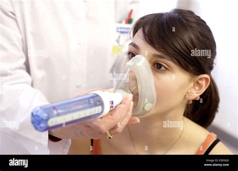 Woman Undergoing A Lung Function Test Using A Peak Flow Meter To Measure Her Expiratory Flow
