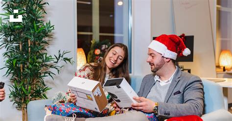 크리스마스 모자와 책을 들고 소파에 앉아 있는 남자와 여자 사진 Unsplash의 무료 크리스마스 이미지