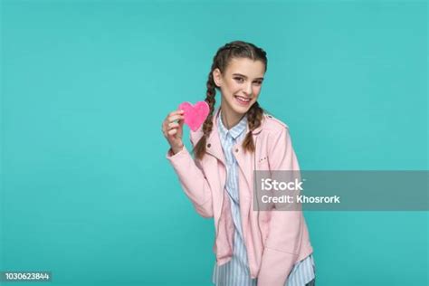 캐주얼 스타일 변 발 헤어스타일에 분홍색 재킷 서 있고 분홍색 하트 모양 보여주는 Toothy 미소와 함께 카메라를 보고 행복 한 아름 다운 여자 감정에 대한 스톡 사진 및