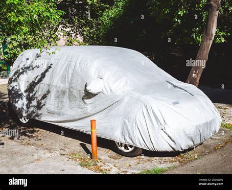 The Car Covered With A Coverstands In The Courtyard Under The Trees