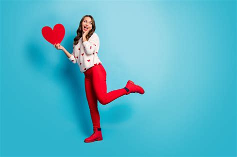 그녀의 전체 길이 몸 크기보기 그녀의 좋은 매력적인 사랑스러운 쾌활한 쾌활한 놀람 장난 소녀 들고 손 심장에 재미 가 고립 된 밝은 생생한 빛나는 활기찬 푸른 색 배경 갈색