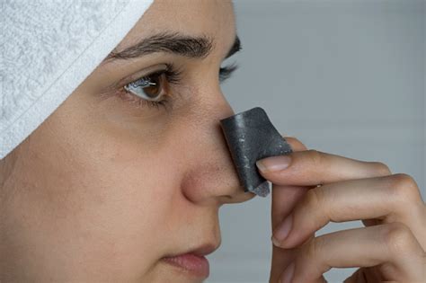 한 여성이 코에서 클렌징 스트립을 제거합니다 코에 검은 점 화장실에서 화장이없는 소녀 스킨 케어 문제 피부 클렌징 자연의 아름다움 자연스러움 블랙 헤드와 코마인 25 29