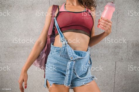 스포츠 가방과 손에 물 한 병을 든 인식 할 수없는 여성이 벽에 기대어 서 있습니다 25 29세에 대한 스톡 사진 및 기타 이미지 25 29세 건강한 생활방식 곱슬