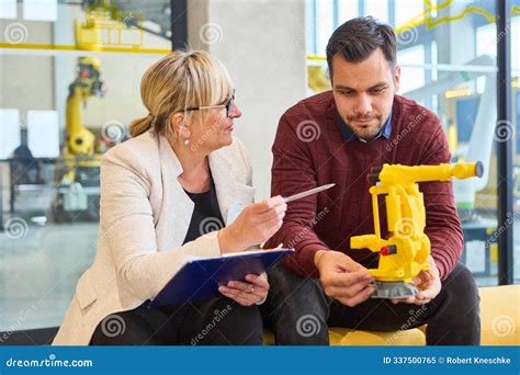 Engineers Discussing Robotic Gripper Arm Development In A Modern