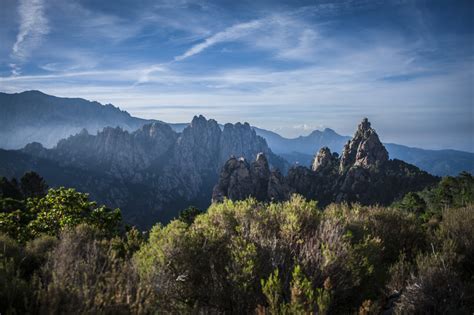 Jagged Rock Formations And Lush Greens Landscape Wallpaper Background