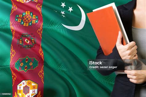 투르크멘 언어 개념을 배운다 배경에서 투르크메니스탄 국기와 함께 서 있는 젊은 여자 책을 들고 교사 오렌지 빈 책 표지 교사 교육 관련 직업에 대한 스톡 사진 및 기타