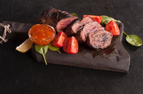 나무 부엌 보드에 피가 약한 로스트의 육즙 쇠고기 스테이크 근처에는 태국 달 콤 하 고 새 콤 한 소스가 있습니다 복사 공간