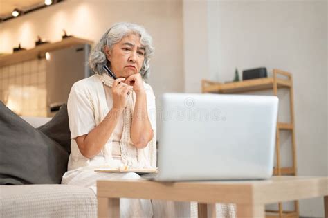 A Perplexed Asian Senior Woman Faces A Problem While Using Her Laptop