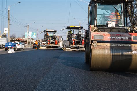 무거운 아스팔트 로드 롤러 무거운 진동 롤러 압축기는 거리의 도로 건설 현장에서 새로운 뜨거운 아스팔트와 아스팔트 파버 기계를 누릅니다 거리에 대한 스톡 사진 및 기타