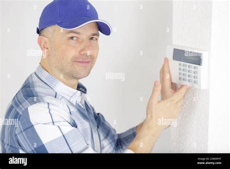 Male Electrician Installing Security System Door Sensor On Wall Stock