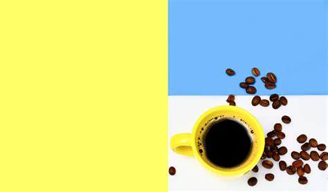 커피의 노란색 컵 그들은 창조적 인 노란색 흰색 파란색 배경의 다양한 천연 커피 콩입니다 모닝 커피 아침 식사의 개념 공간을