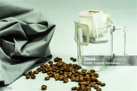 분쇄 커피 커피 방울 용 가방 및 테이블 위의 투명한 머그잔 커피 원두가있는 회색 배경에 커피를 떨어 뜨립니다 커피는 쿡을 사용하여 드립 추출하여 준비합니다 0명에 대한