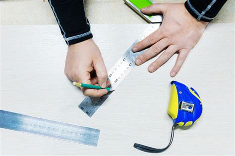 나무 판자를 측정 하 고 연필로 표시 하는 테이프 측정을 사용 하 여 목공 망 손을 닫습니다 위에서 보기 Diy에 대한 스톡