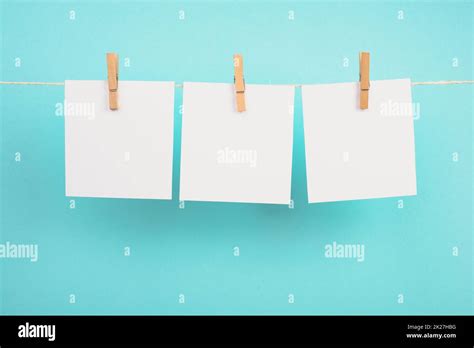 empty white sheets of paper in a row hanging on a string copy space