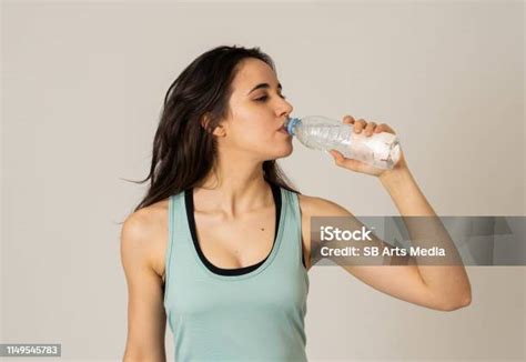 아름 다운 피트 니스 선수의 초상화 젊은 라틴어 여 자가 물병을 들고 운동 후에 회색 배경에 고립 된 운동을 하는 것은 건강 피트 니스 스테이 수 화 개념에 혜택을 제공