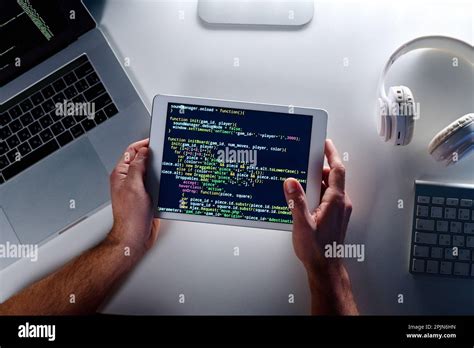Top View Of Tablet Screen With Coded Data Held By Male Programmer Using Or Creating New Software