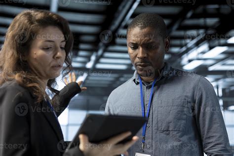 Team Of Engineers In Data Center Talking Using Tablet To Do Network Virtualization Coworkers