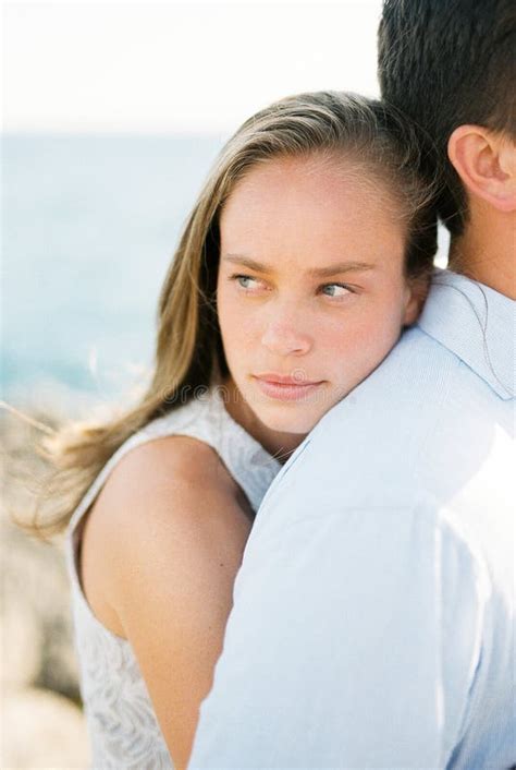 Young Woman Hugs A Man From Behind With Her Head Resting On His