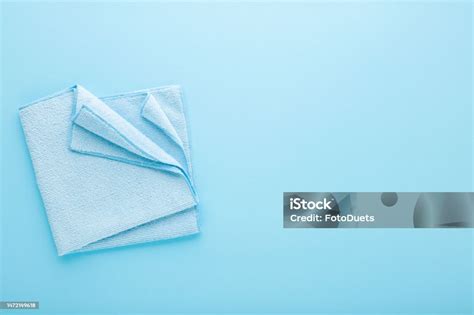 밝은 파란색 테이블 배경에서 닦는 다양한 표면을 위한 접힌 마른 부드러운 극세사 걸레 파스텔 색상 근접 촬영 텍스트를위한 빈 장소 하향식 보기 부드러움에 대한 스톡 사진 및