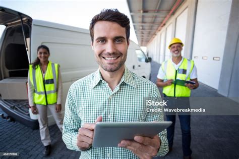 디지털 태블릿 및 배경에서 서 있는 근로자를 사용 하 여 관리자의 경영자에 대한 스톡 사진 및 기타 이미지 경영자 배달