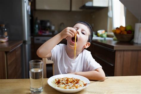 Garotinho Comendo Com As Mãos Prato De Massa Foto Grátis