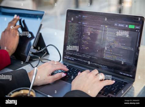Female Programmer Writes Some Code And Drinks Coffee While Sitting Near Her Colleague Stock