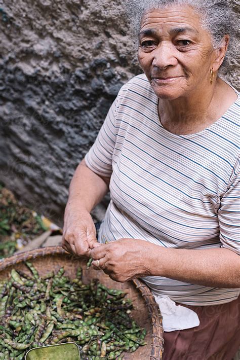 Aged Woman Shelling Beans While Sitting On Street By Stocksy Contributor David Prado Stocksy