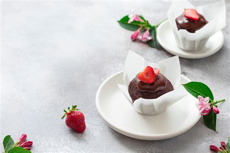 흰 종이에 초콜릿 머핀 두 개를 넣고 초콜릿 시럽을 붓고 신선한 딸기로 장식했습니다 갈색에 대한 스톡 사진 및 기타 이미지 갈색 공휴일 과일 Istock