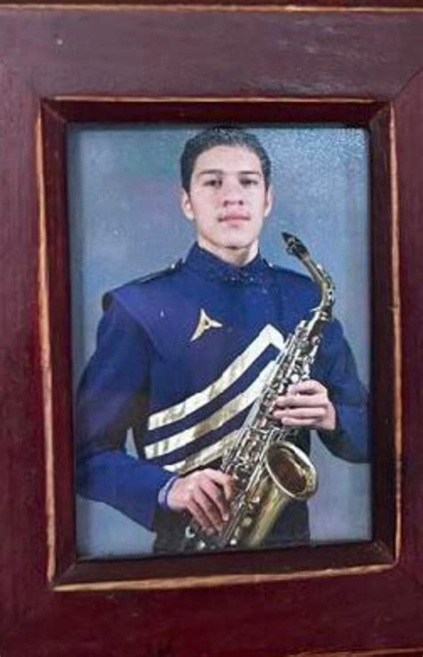 A Man In Uniform Holding A Saxophone And Wearing A Blue Jacket With Gold Trims